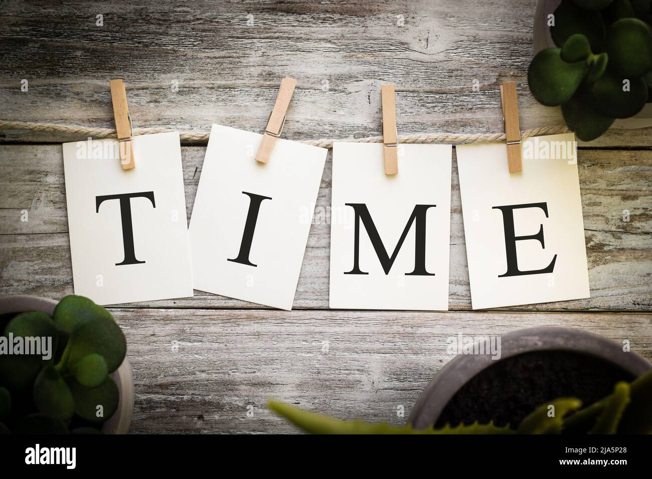 A set of printed cards spelling the word TIME on an aged wooden ...