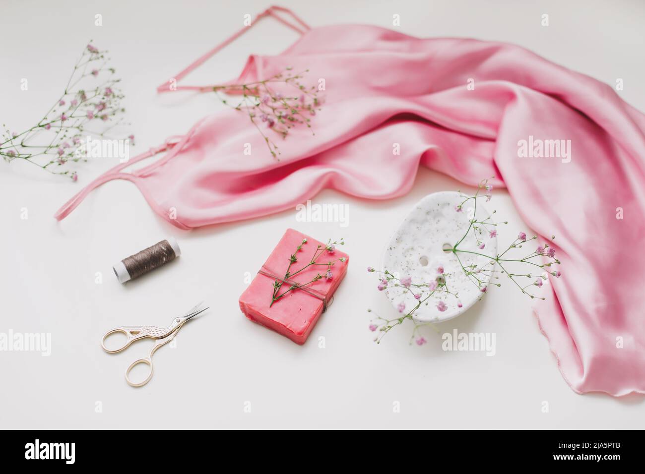 Composition with pink silk fabric, gift in craft paper and threads and ...