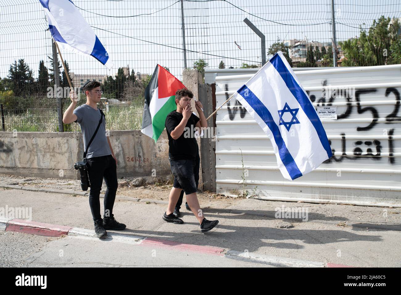 A palestinian teenager carries palestine flag between two settlers ...