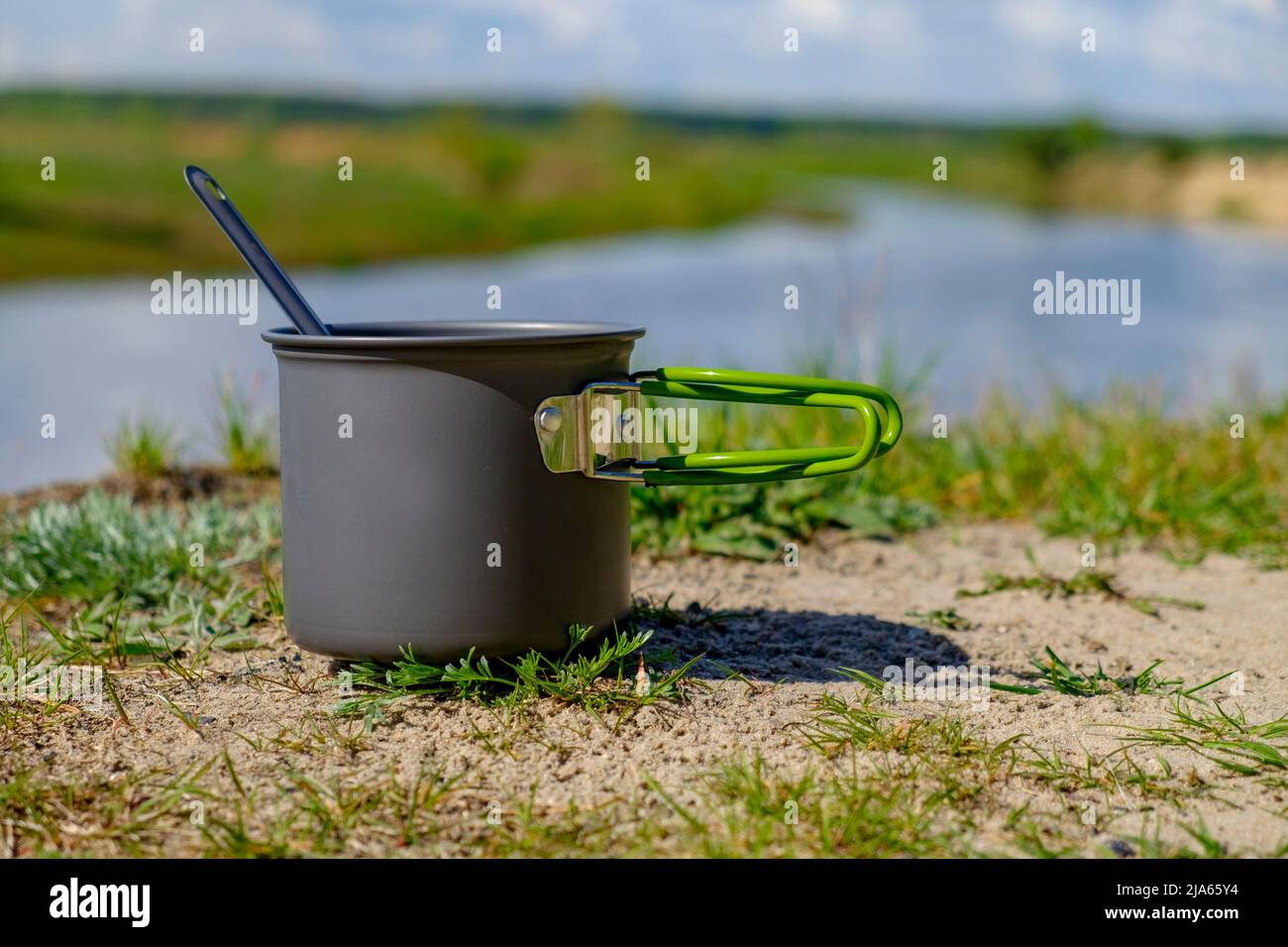 Camping pot and spoon on river background Stock Photo - Alamy