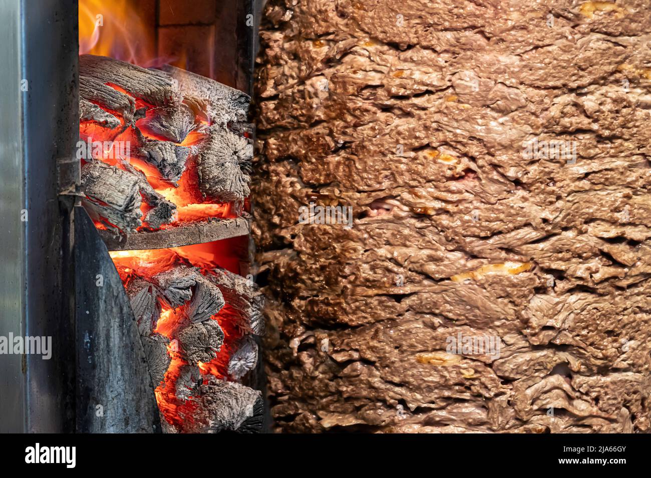Doner kebab meat on skewers in front of the grill in the restaurant ...