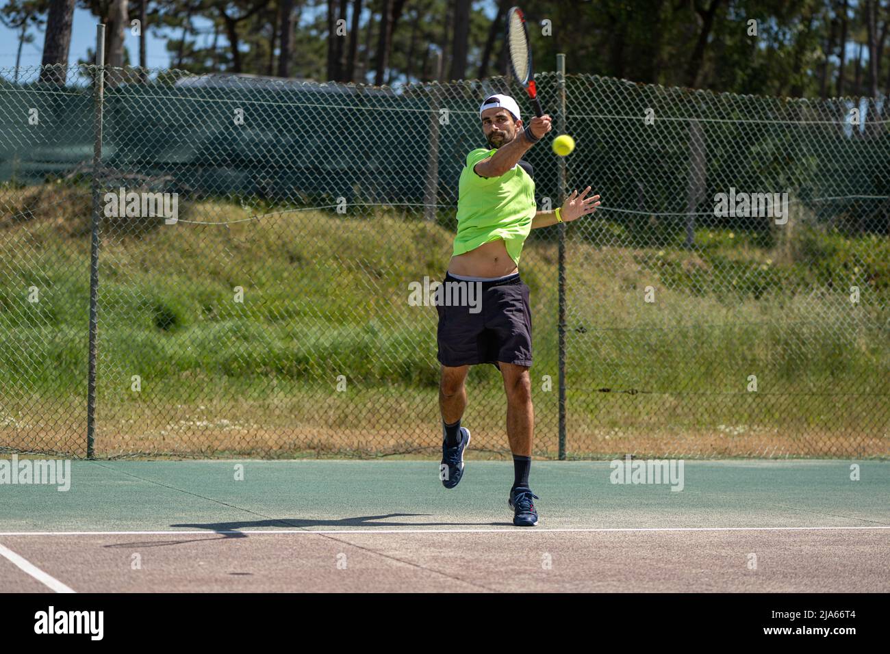 Tennis player hitting forehand at ball with racket on court Stock Photo ...