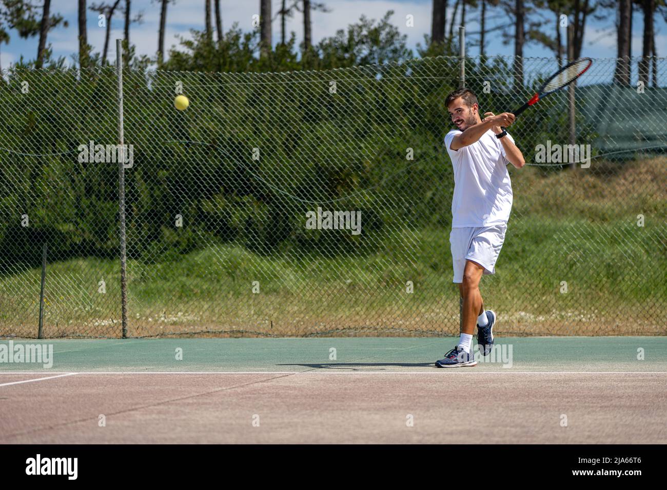 Tennis player hitting forehand at ball with racket on court Stock Photo ...