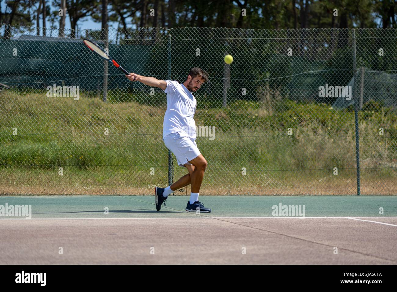 Tennis player hitting backhand at ball with racket on court Stock Photo ...