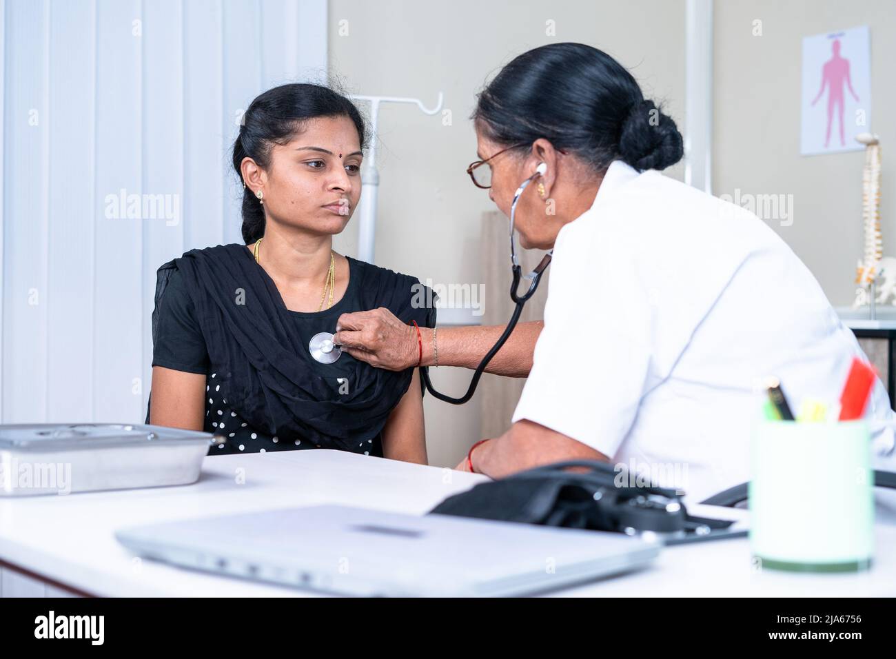 Doctor examining sick woman patient at hospital using stethoscope ...