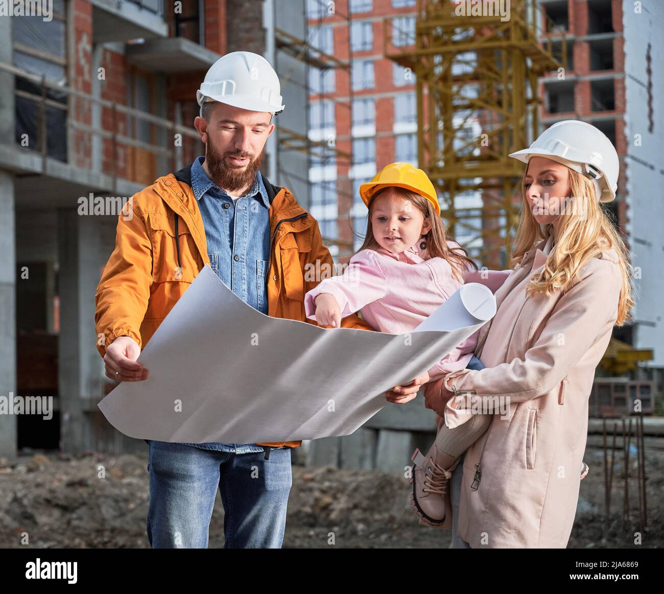 Family with child studying architectural drawings outside apartment ...