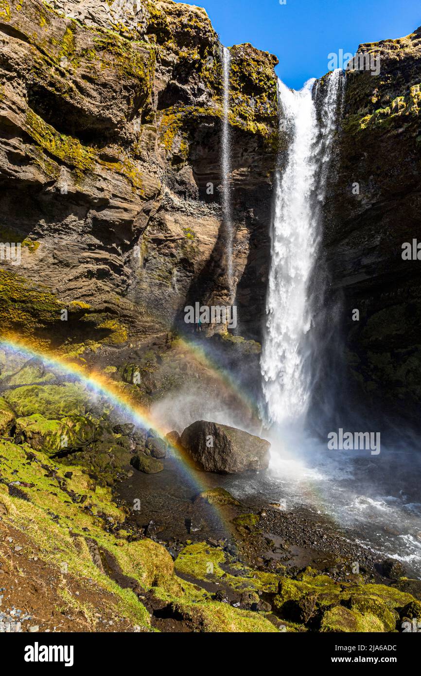 At Kvernufoss thundering falls rushing over sheer, moss-covered cliffs ...