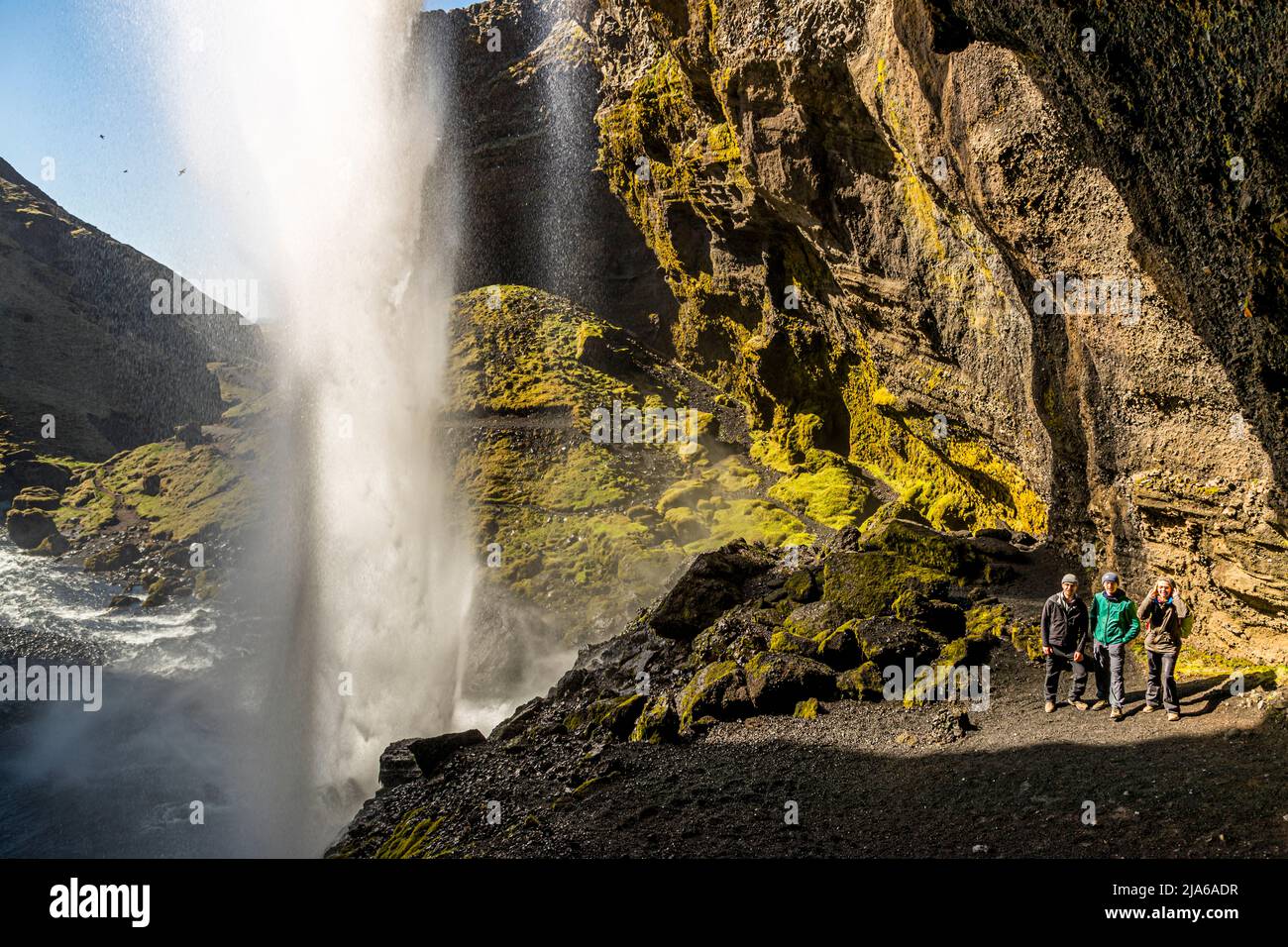 At Kvernufoss thundering falls rushing over sheer, moss-covered cliffs ...