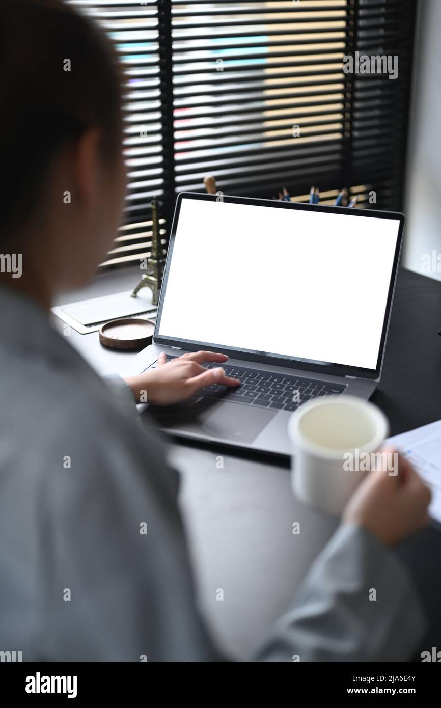 Female employee using laptop computer and drinking hot coffee. Over ...