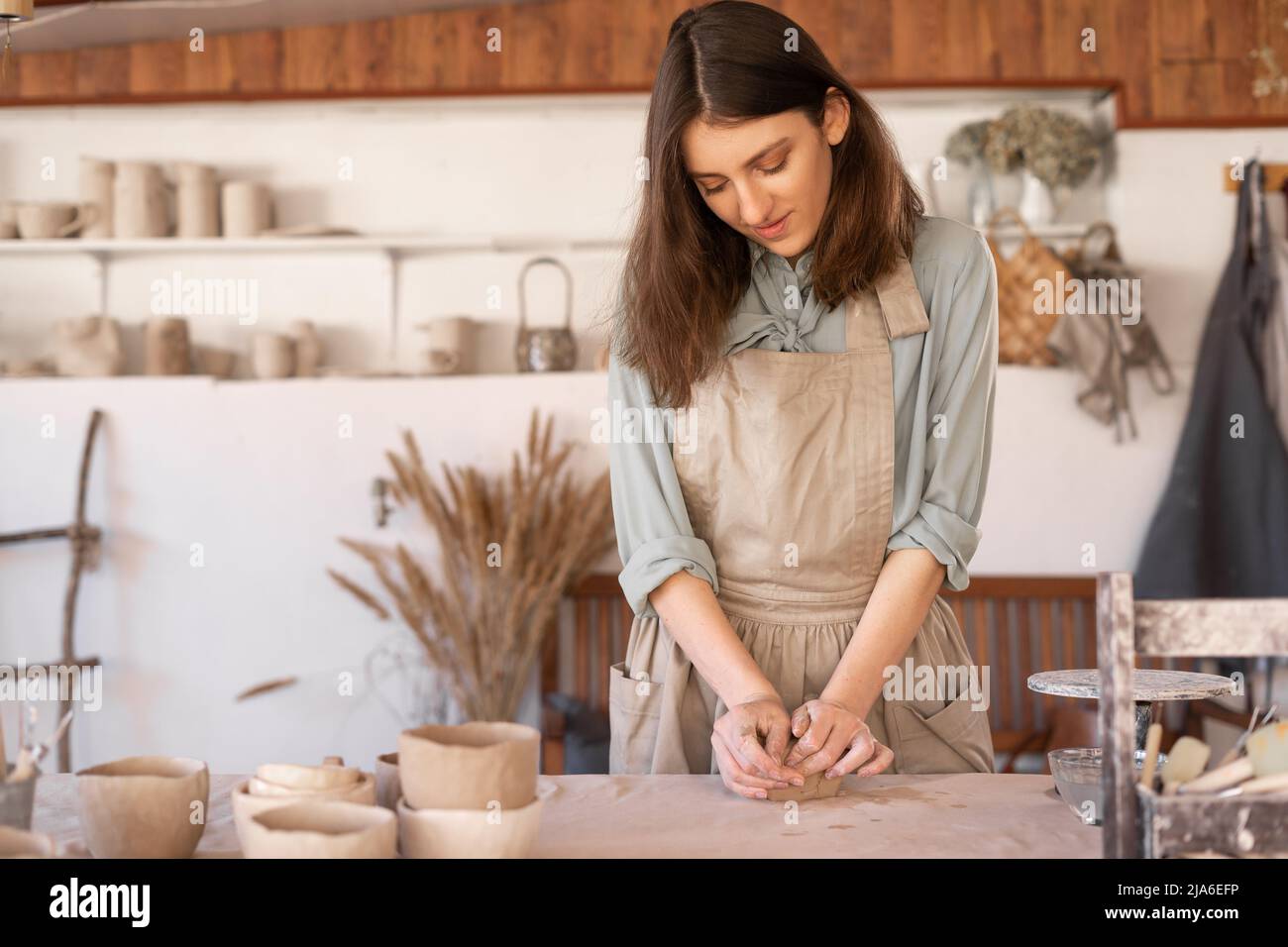 Master of art ceramics at work happy woman in an apron works in a ...