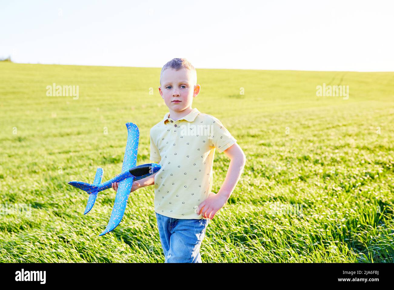 Boy runs with toy airplane in summer through field. Happy child running ...
