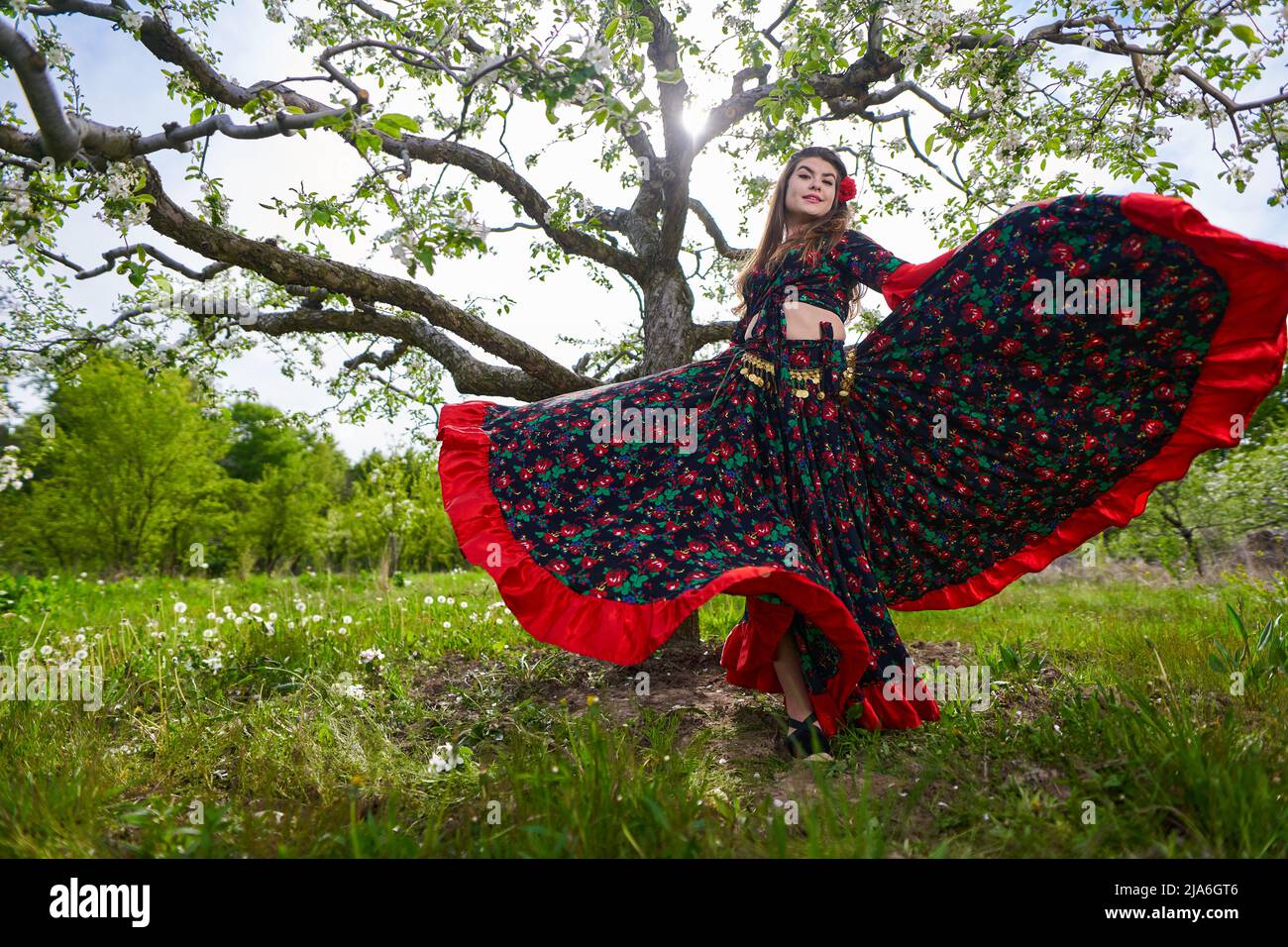 Young woman in traditional gypsy dress, performing a dance in an apple ...