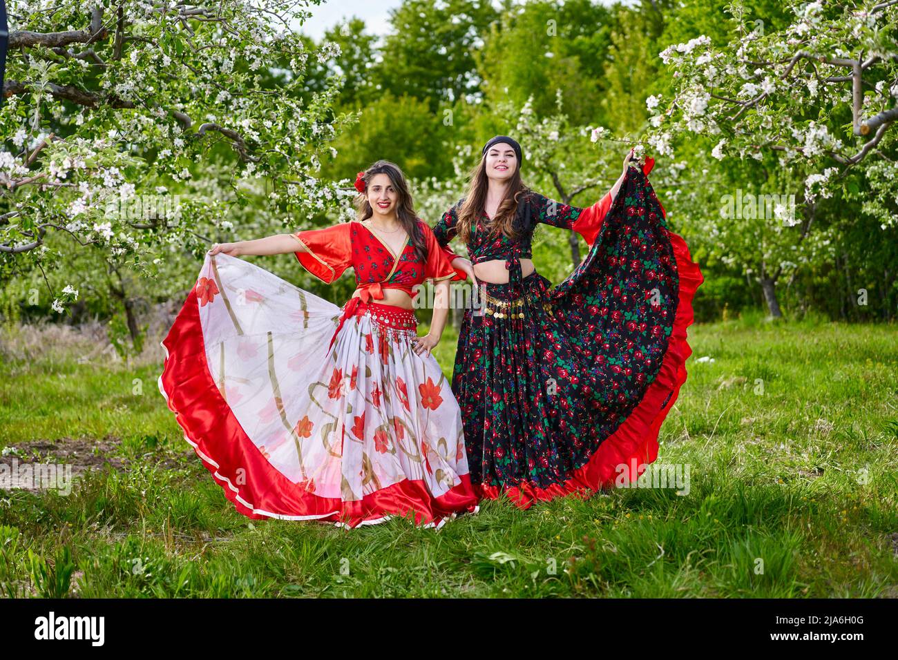 Two young women in traditional gypsy costume dancing in a flowering ...