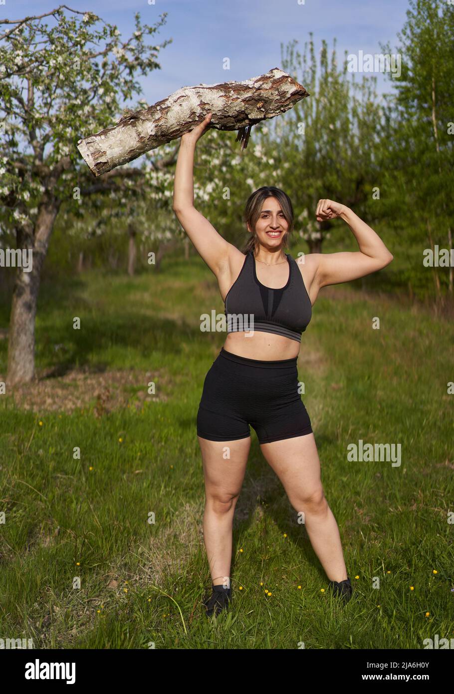 Strong size plus indian woman doing fitness workout outdoor with a log ...