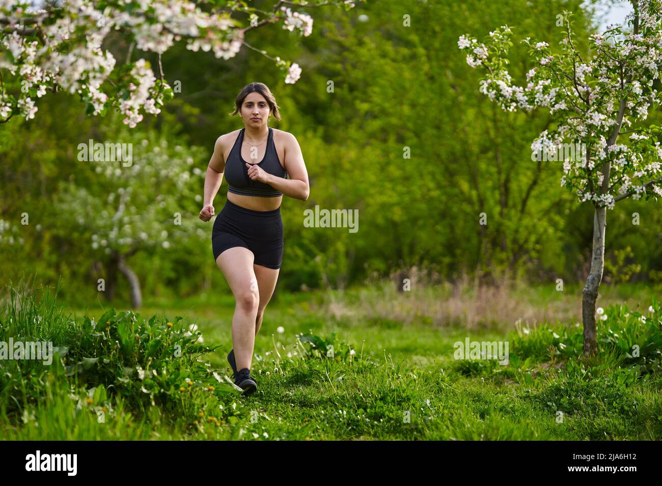 Beautiful plus size runner indian woman running on the grass in the ...