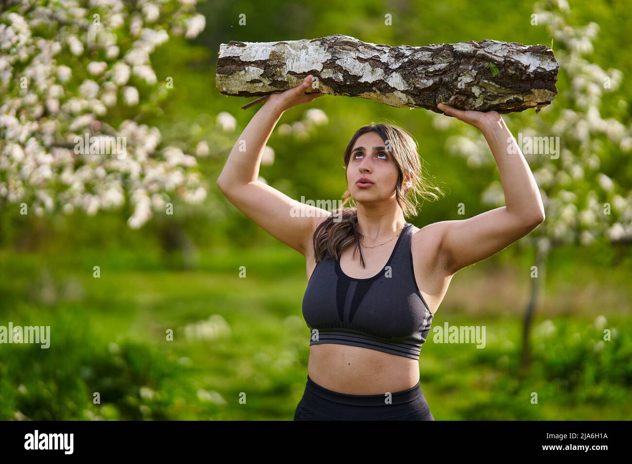 Strong size plus indian woman doing fitness workout outdoor with a log ...