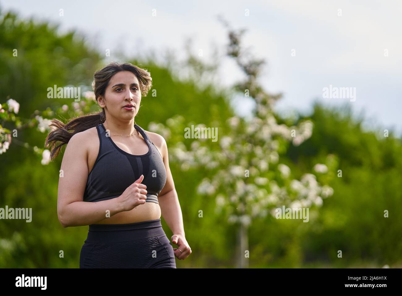 Beautiful plus size runner indian woman running on the grass in the ...
