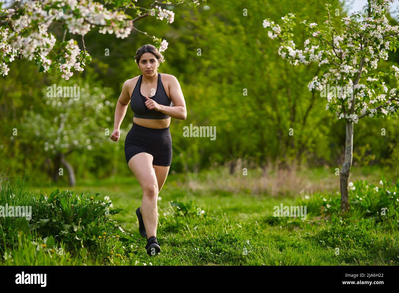 Beautiful plus size runner indian woman running on the grass in the ...