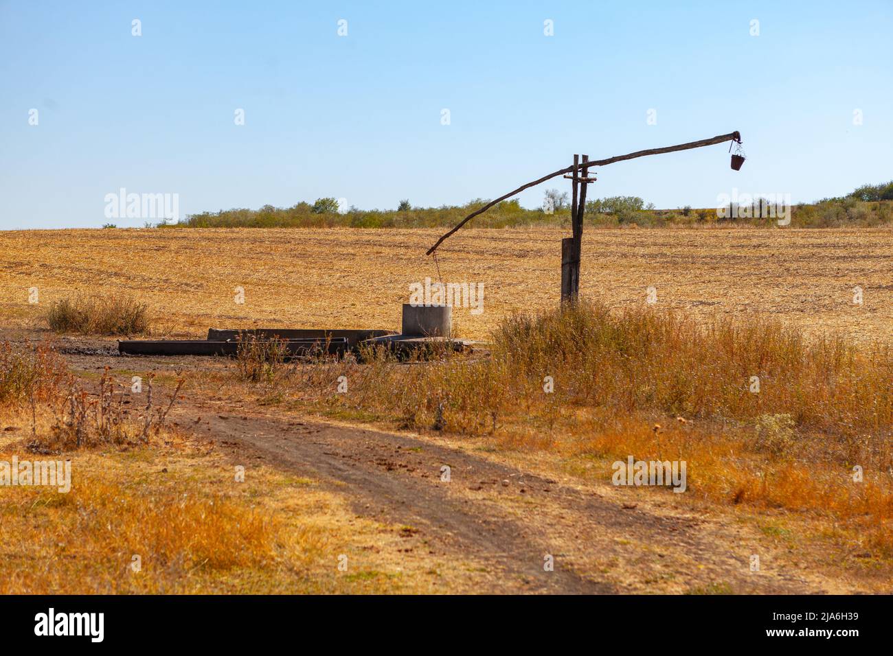 Ancient well with old lifting mechanism of water . Agriculture field in ...