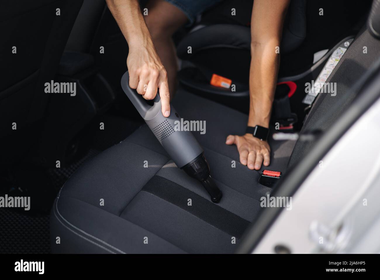 Close up of male using portable vacuum cleaner in her car. Electrical ...