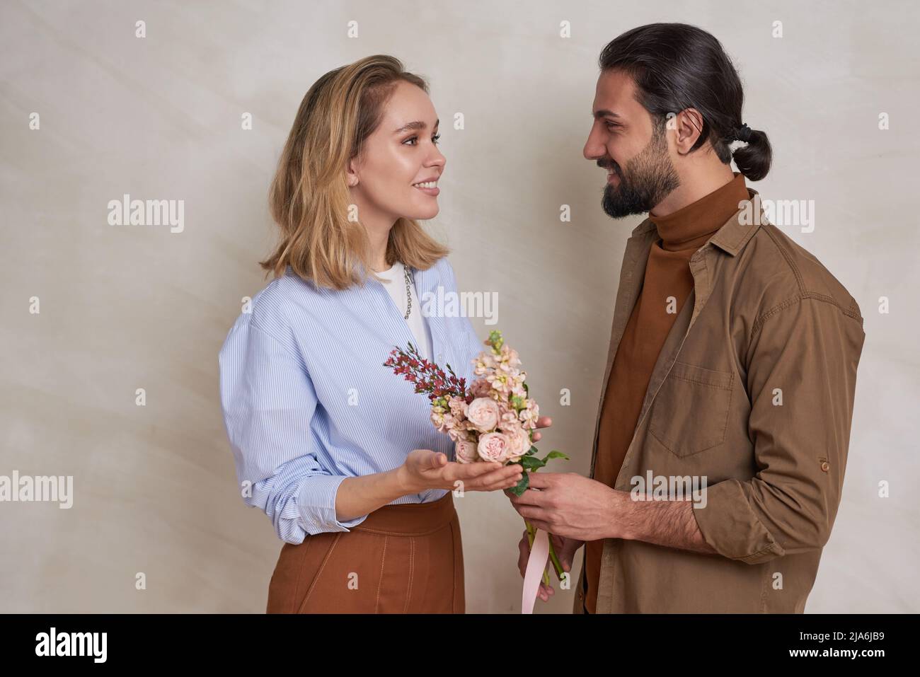Portrait of romantic young man giving beautiful flowers to his ...