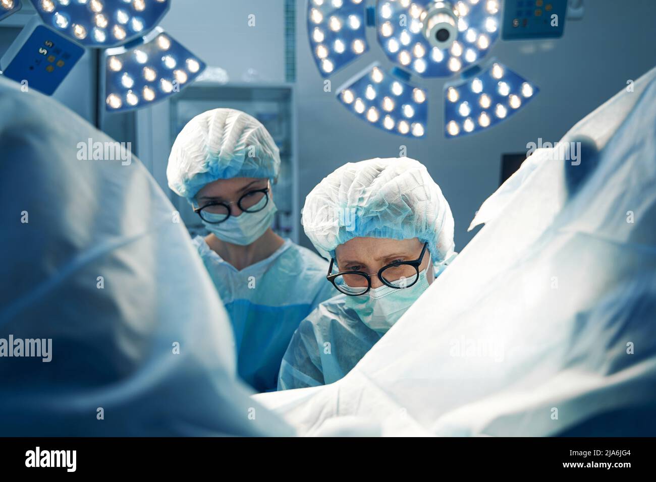 Elderly woman surgical specialist and nurse in glasses conducting ...