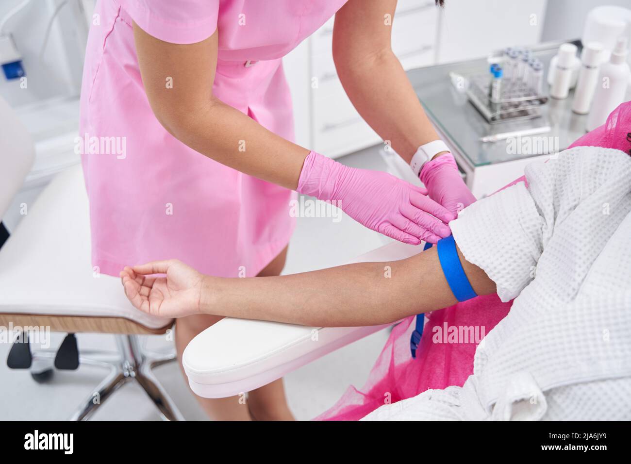 Medical worker setting tourniquet on female arm before intravenous ...