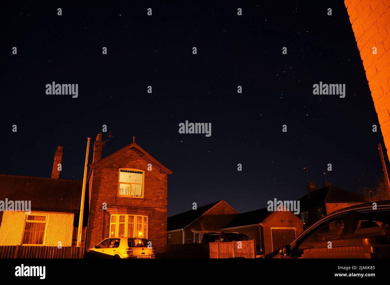 Looking up at stars in the night sky from an illuminated suburban ...