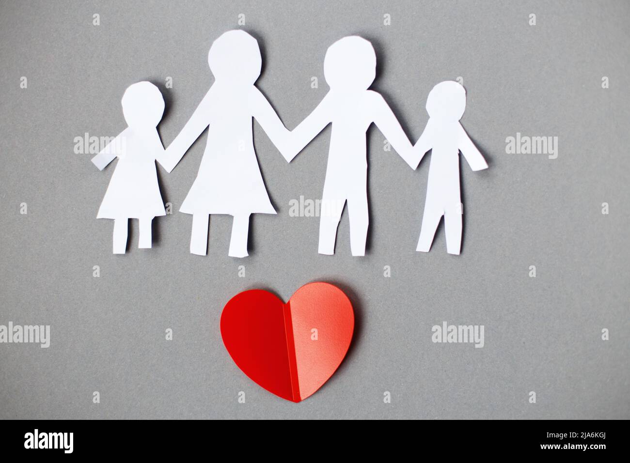 Happy paper cut family holding hands on gray background with red heart ...
