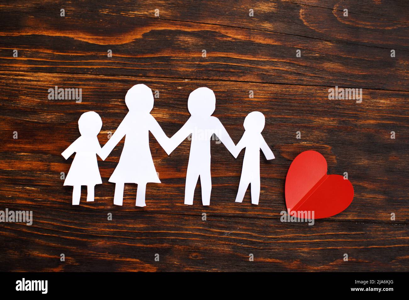 Happy paper cut family holding hands on a brown wooden background with ...