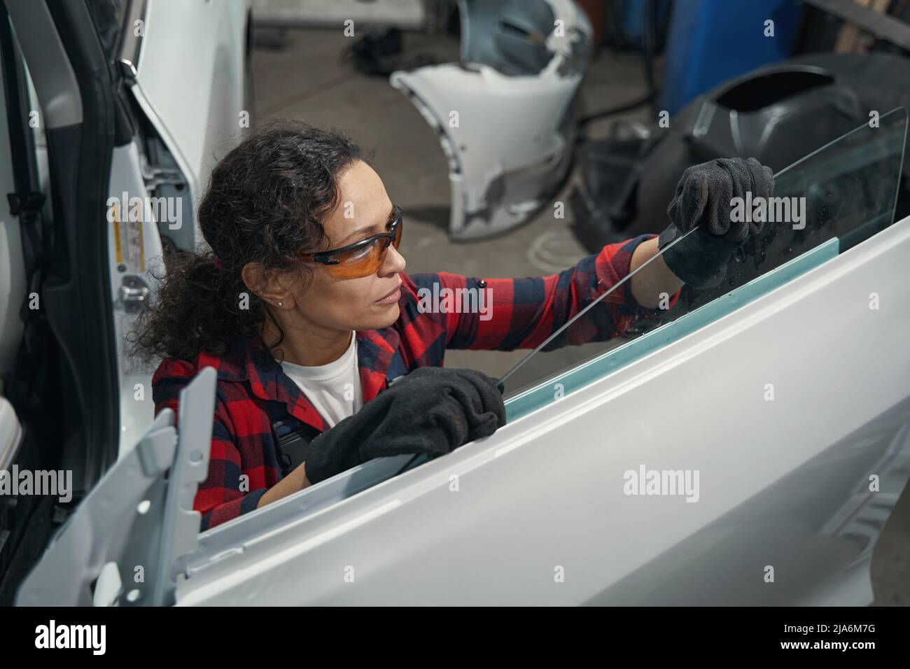 Female auto mechanic repairing vehicle door in garage Stock Photo - Alamy
