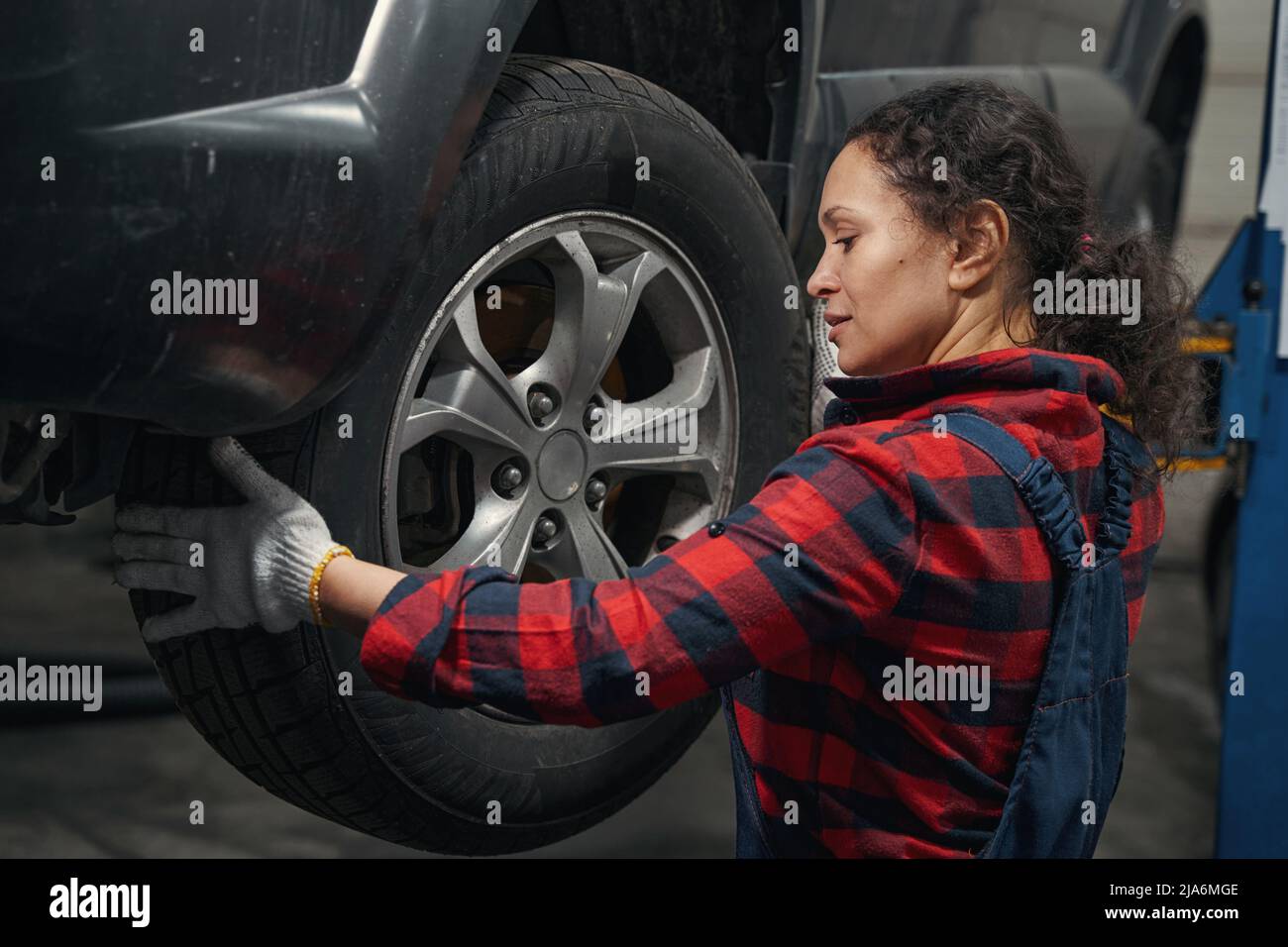 Woman auto mechanic replacing car wheel in garage Stock Photo - Alamy