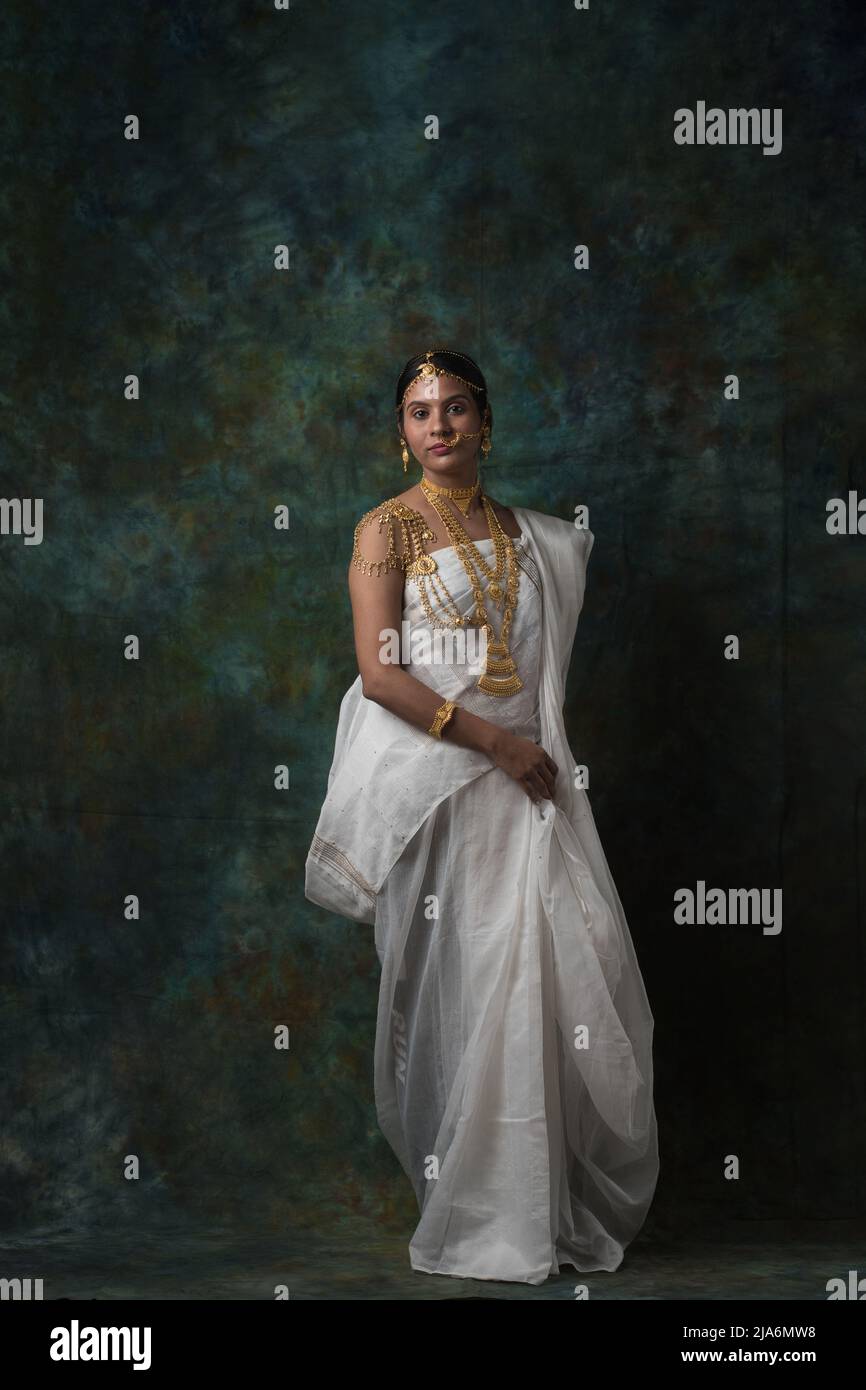 indian woman in a traditional white saree and gold jewellry to ...