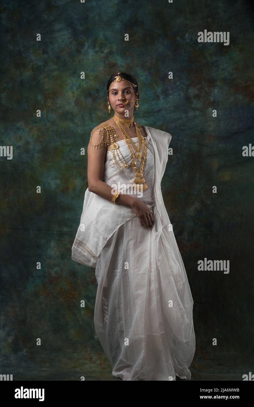 indian woman in a traditional white saree and gold jewellry to ...