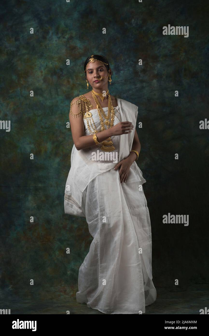 indian woman in a traditional white saree and gold jewellry to ...
