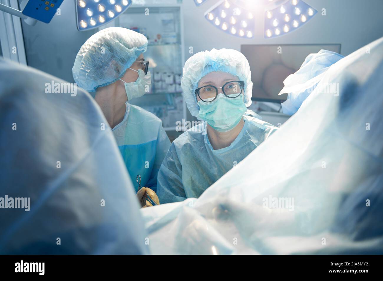Woman surgeon getting distracted from operating and looking to side ...