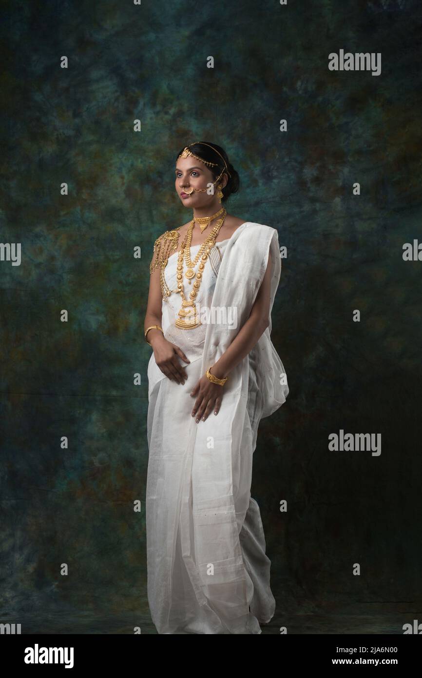 indian woman in a traditional white saree and gold jewellry to ...