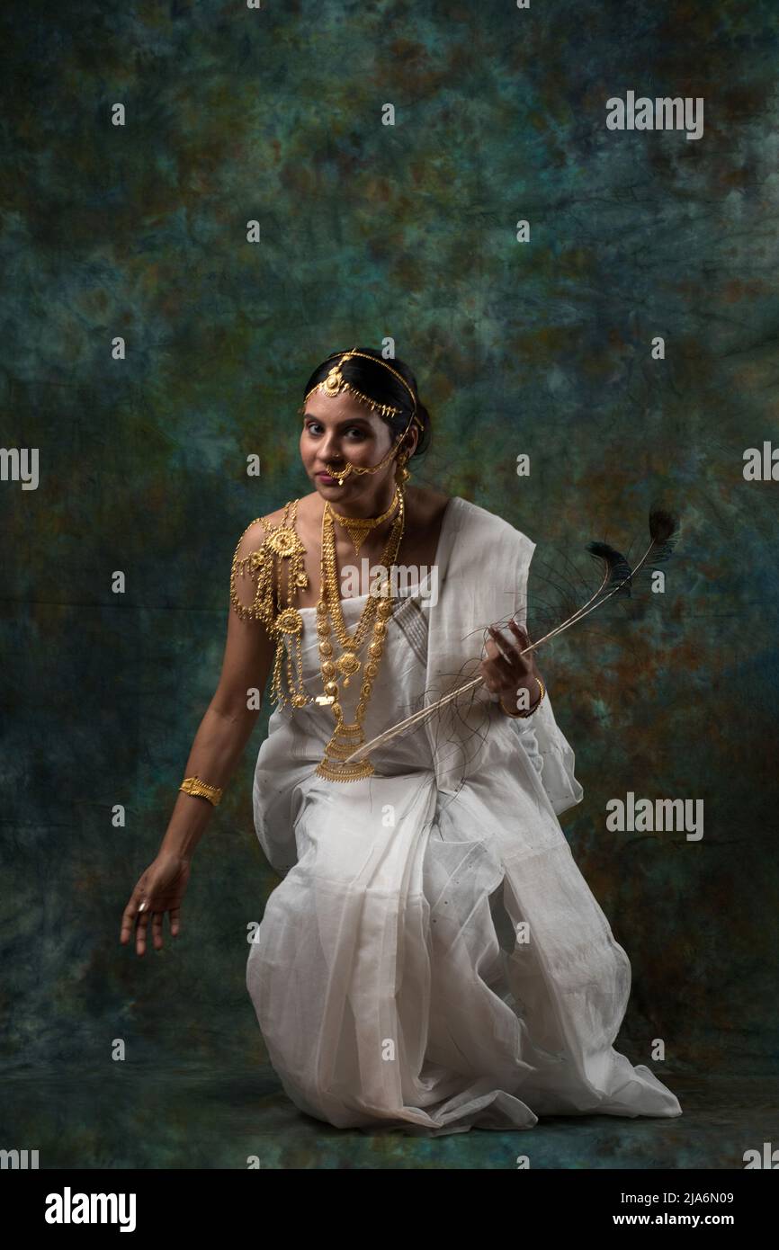 indian woman in a traditional white saree and gold jewellry to ...