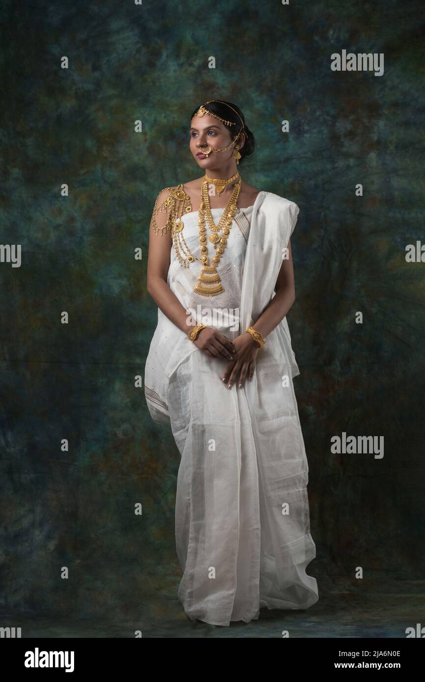 indian woman in a traditional white saree and gold jewellry to ...