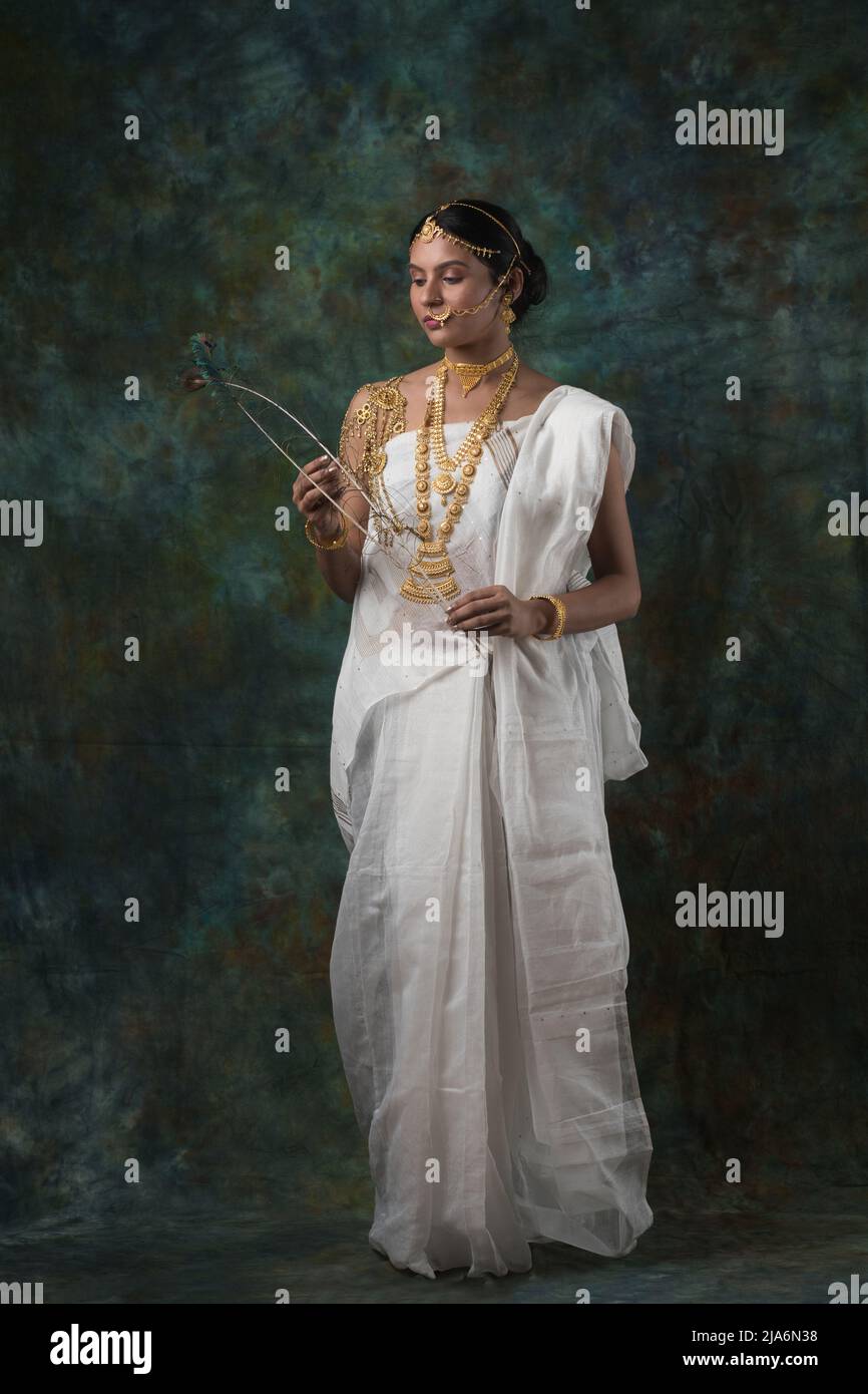 indian woman in a traditional white saree and gold jewellry to ...