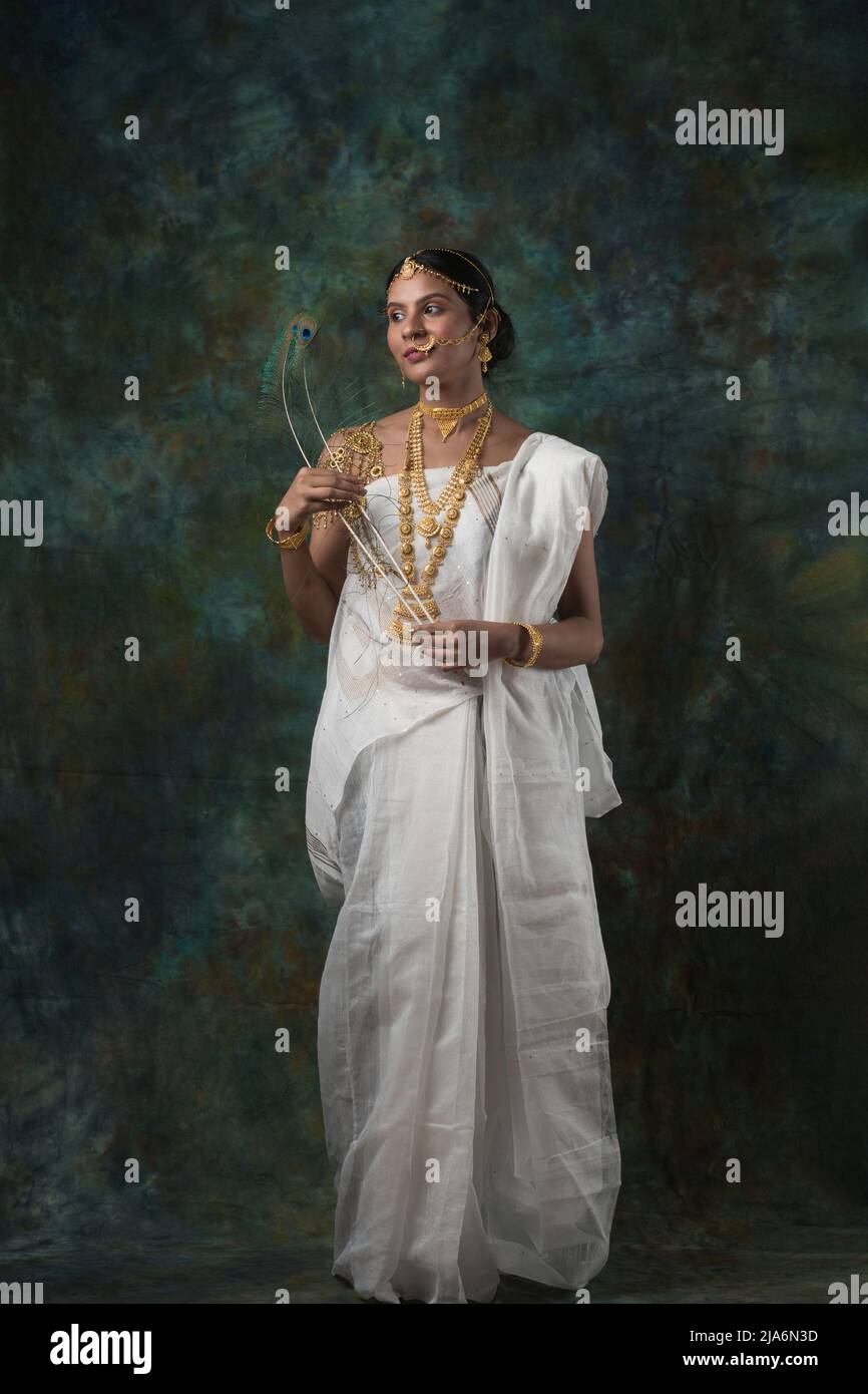 indian woman in a traditional white saree and gold jewellry to ...