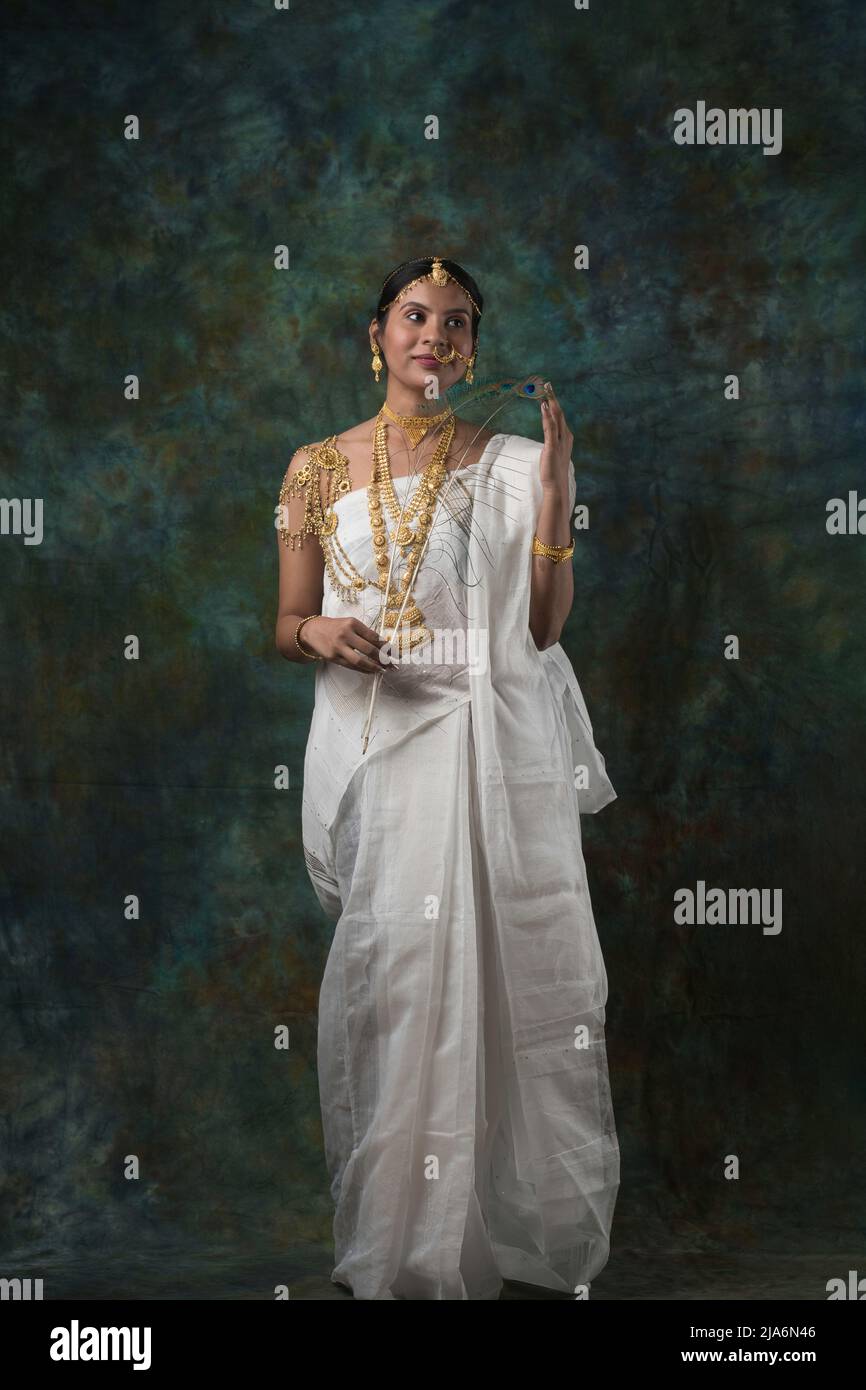 indian woman in a traditional white saree and gold jewellry to ...