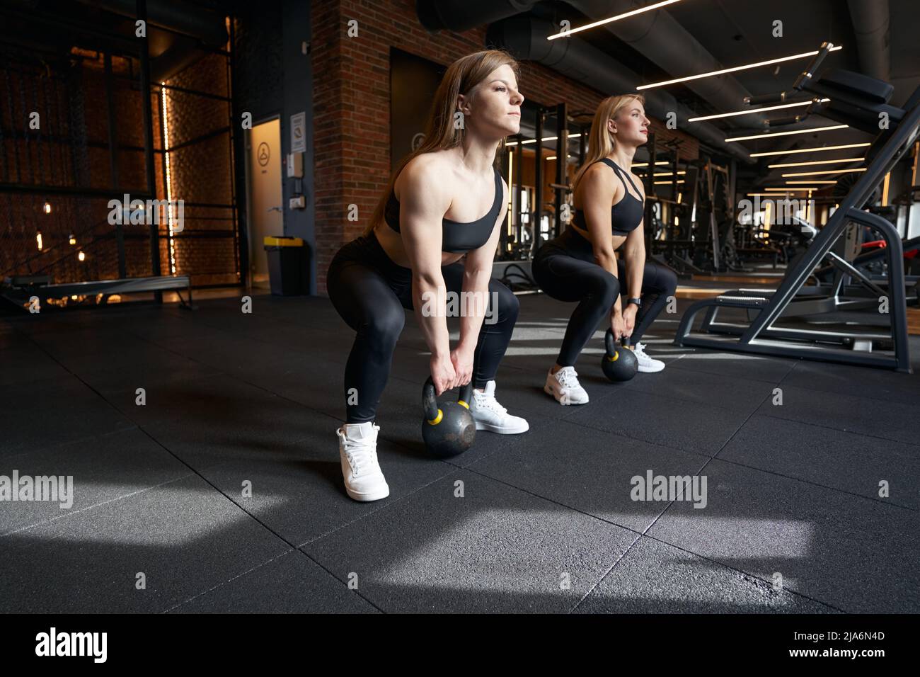 Sportswomen performing weight-lifting exercise in fitness studio Stock ...