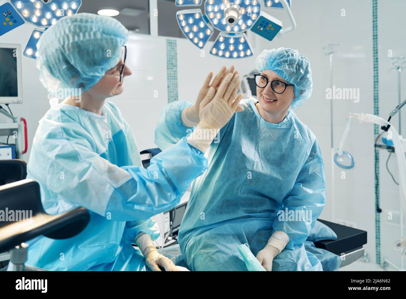 Nurses giving high five to each other on operation bed Stock Photo - Alamy