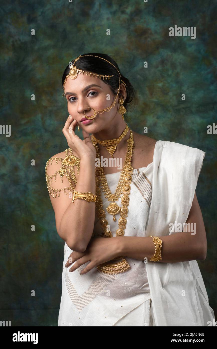 Indian female model wearing a white saree and gold jewellry sporting a ...
