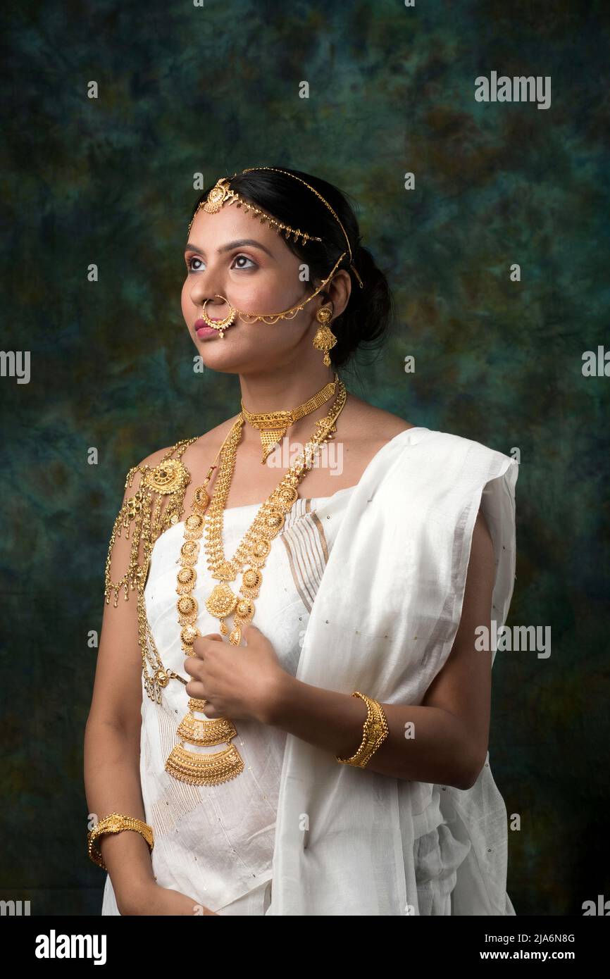 indian woman in a traditional white saree and gold jewellry to ...