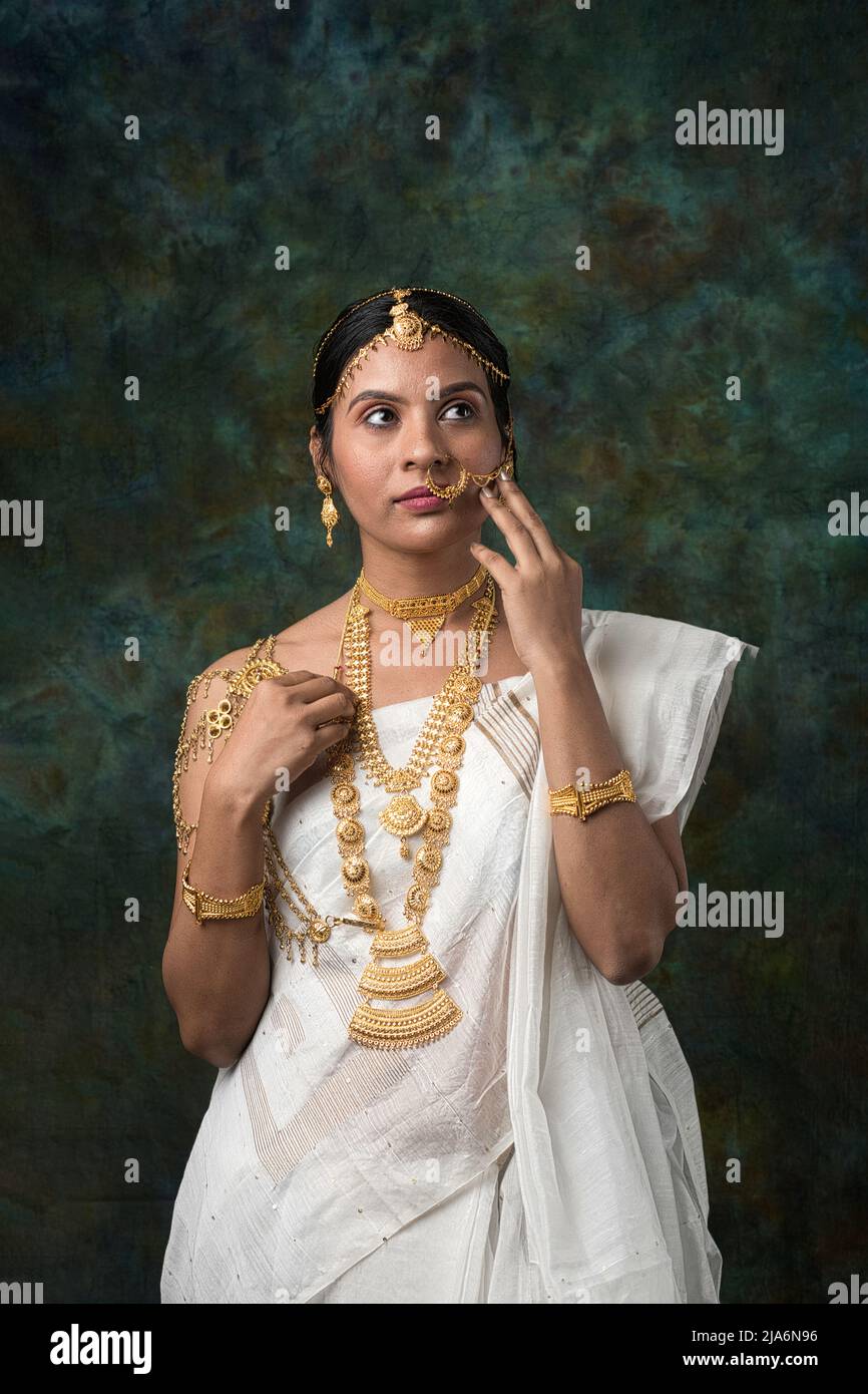 indian woman in a traditional white saree and gold jewellry to ...