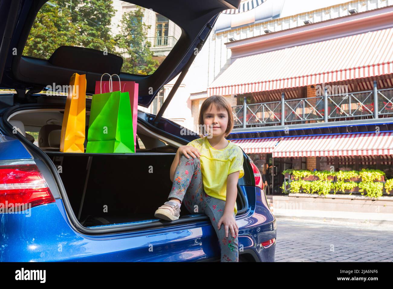 A girl is sitting in a car trunk and posing for a camera Stock Photo ...