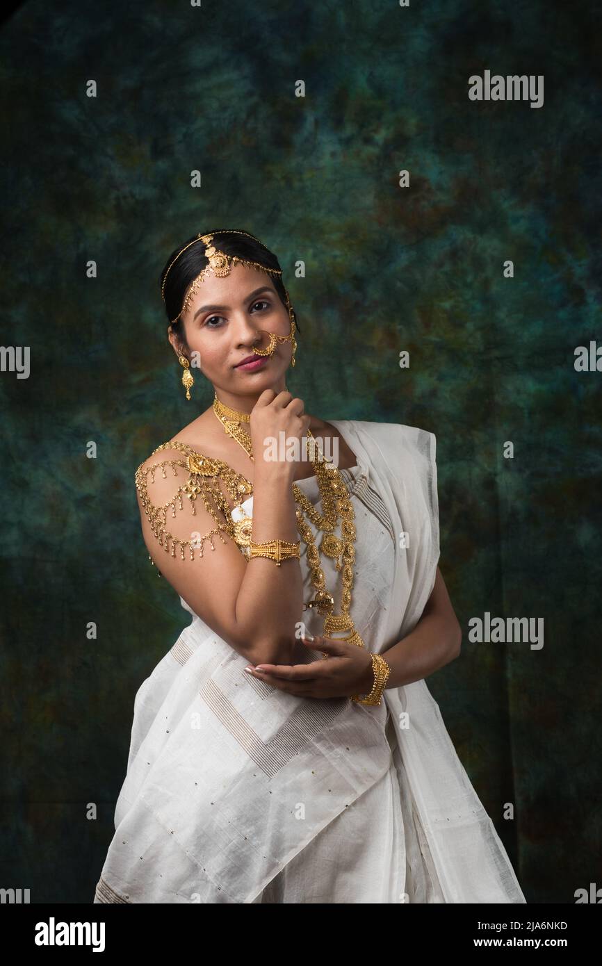 Indian female model wearing a white saree and gold jewellry sporting a ...