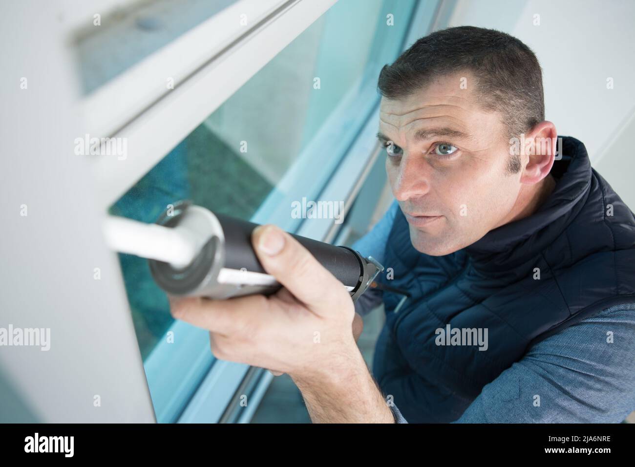 man using a silicone gun to repair a window Stock Photo - Alamy